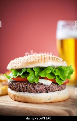 Hamburger, french fries and glass of cold beer on a white wooden ...