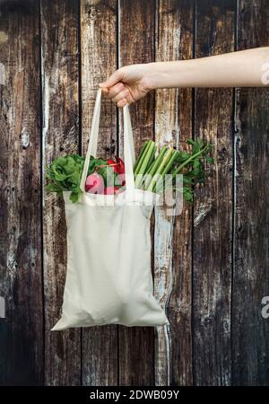 Female hand holding eco or reusable shopping bag against white ...