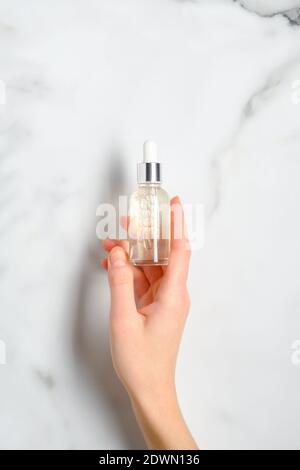 Dropper with transparent cosmetic liquid over blue glass background ...