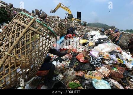Scavengers are active in piles of rubbish in the landfill (TPA) of ...
