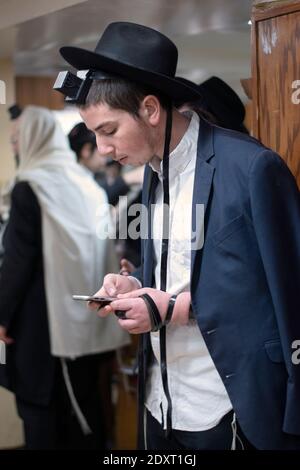 Orthodox Jewish man using a mobile phone in a rowing boat, Hollow Ponds ...