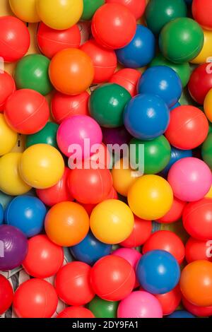 Collection of multi colored plastic balls floating in a tub of water is ...