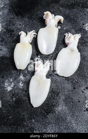 Raw mini cuttlefish on the table. Black background. Top view Stock ...