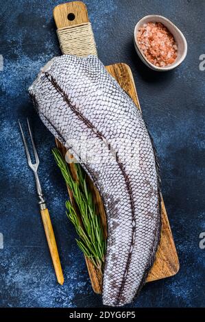 Fresh Raw grenadier macrurus white fish on a wooden cutting board. Blue ...