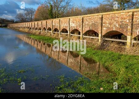 Arches of Maud Heath's causeway reflected by flood water of River Avon ...