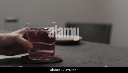 man pouring purple drink into tumbler glass near window, wide photo ...