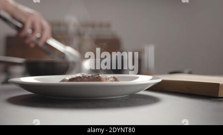 Man hand put cooked steak on white plate for resting before serving ...