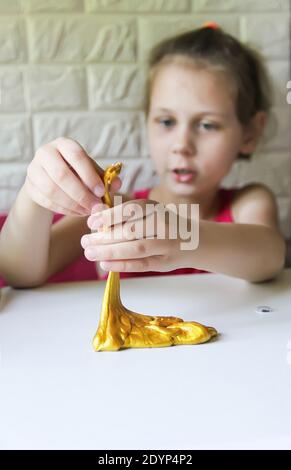 Little girl playing with the gold slime. Sensory activity for child ...