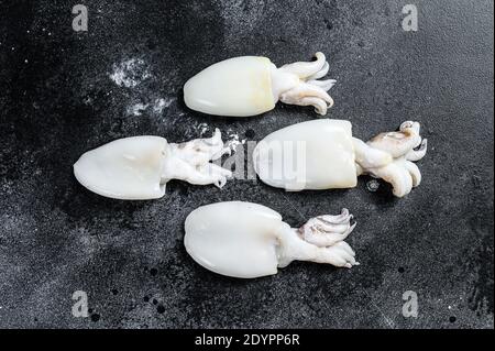 Raw mini cuttlefish on the table. Black background. Top view Stock ...