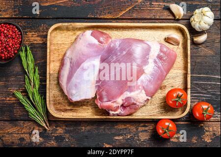 Raw fillet of farm Turkey thigh. Dark wooden background. Top view. Copy ...