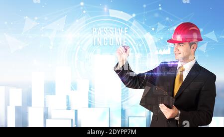 Handsome businessman with helmet drawing PASSIVE INCOME inscription ...