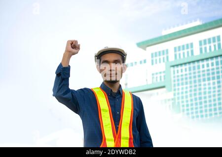 Engineering holding hand success and wears a white safety hat while ...