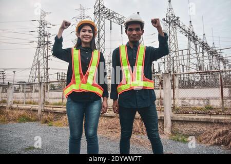 Two Electrician Engineer high voltage tower background Stock Photo - Alamy