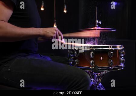 Drum sticks hitting snare drum with splashing water on black background ...