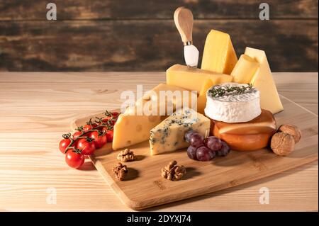 Maasdam cheese with walnuts, blue grapes, and rosemary on a black ...