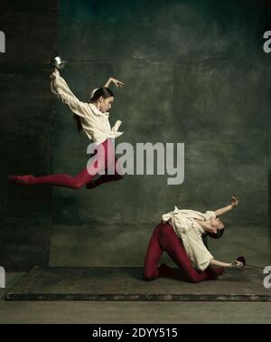 Attacking. Two young female ballet dancers like duelists with swords on ...