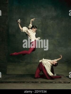Attacking. Two young female ballet dancers like duelists with swords on ...