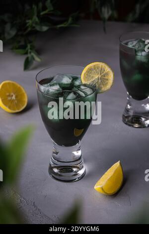a glass of yellow mocktail served with ice, basil and cherries as ...