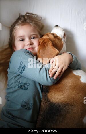 little cute girl hugs a beagle dog sitting on the windowsill Stock ...