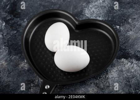 Two white eggs on heart shaped pan Stock Photo - Alamy