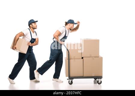 side view of interracial couriers in medical masks holding packages on ...