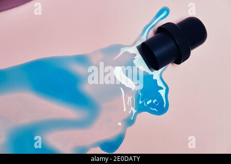 Top view of liquid detergent spilled from plastic cap on pink ...