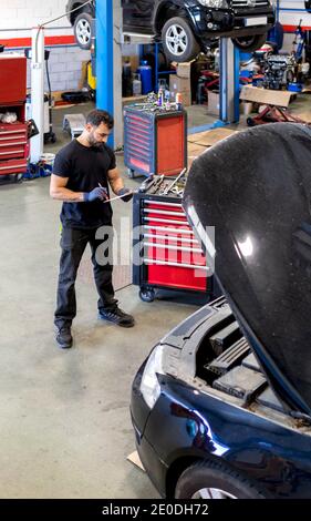 auto mechanic with clipboard and man at car shop Stock Photo - Alamy