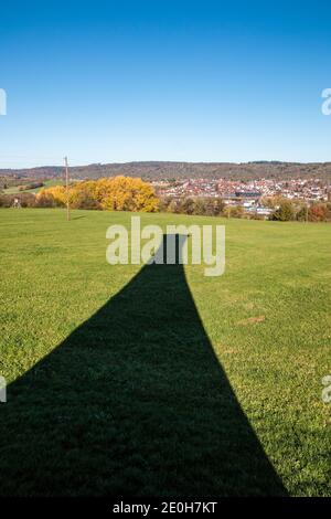 Black shadow of a tower on the green field near the town Stock Photo ...