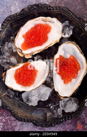 Red caviar in the sea shells on gray graphite background. Macro picture ...