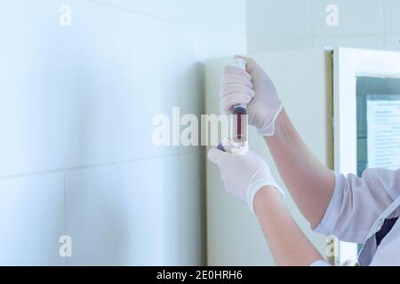 A person wearing a protective glove pours organic waste, including ...