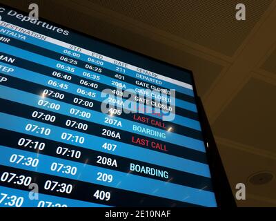 A blue digital screen at an airport announcing time and gate info for ...