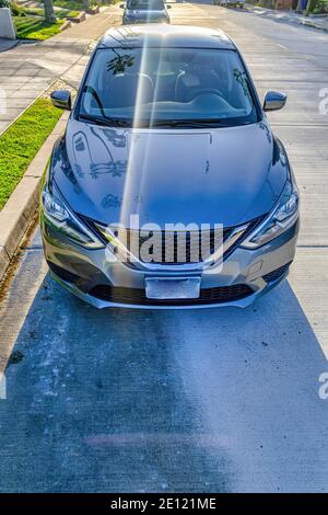 Gray shiny car parked in quiet area on asphalt road on blurred bokeh ...