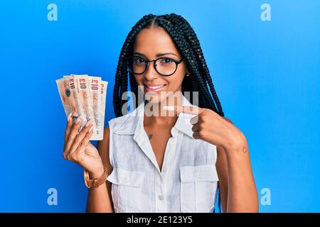 Beautiful hispanic woman holding 10 united kingdom pounds banknotes ...