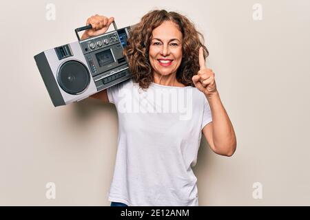 excited brunette woman holding boombox and laughing at camera isolated ...