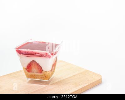 A strawberry cheesecake in a plastic cup with fresh strawberries and ...