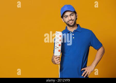 Portrait of a cheerful electrician in the cap screwing the light bulb ...