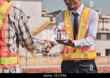 Two Engineer shake hand agree building house project on site ...