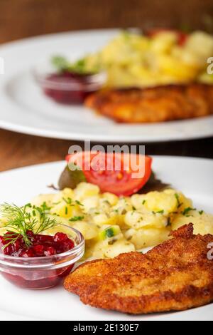 German schnitzel with roasted potatoes and cranberry sauce on black ...