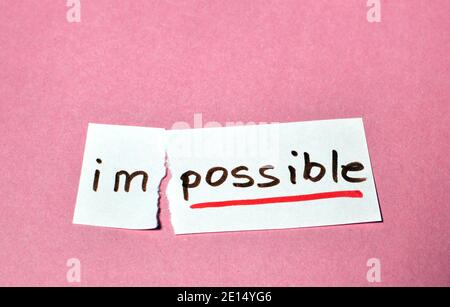 Concept of the word impossible written by hand and cut as possible, put ...