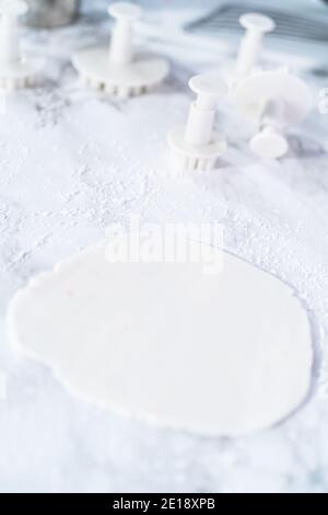 Rolling out fondant to cut snowflake shapes with cookie cutters Stock ...