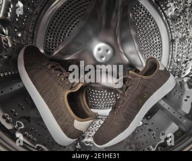 Sports sneakers in metal drum of washing machine close-up. Wide angle ...