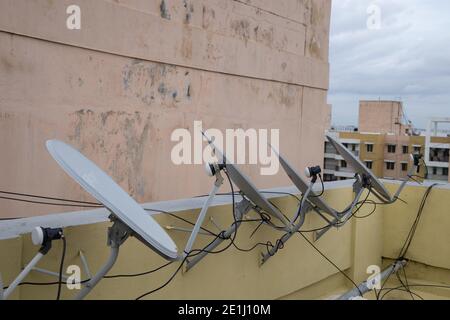 A row of dish antennas fixed on the wall of the roof top and pointing ...