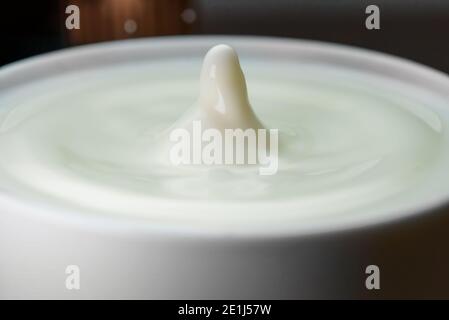 Milk drop falls into the filled cup Stock Photo - Alamy