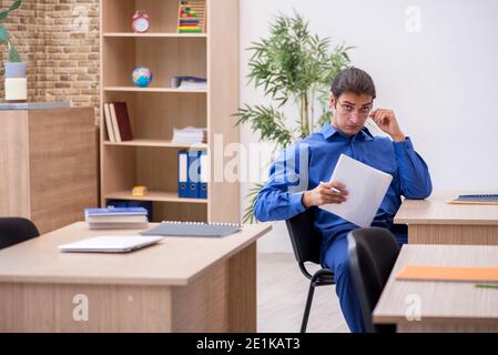 Young teacher checking notes in the classroom Stock Photo - Alamy