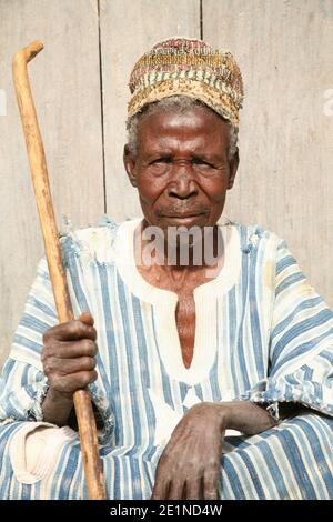 Portrait of a blind Ghanaian man in front of his home in traditional ...