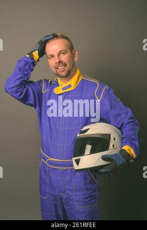 Blond bearded man motorcyclist with goatee in full gear against gray ...