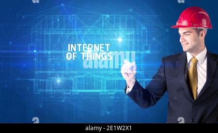 Handsome architect with helmet drawing INTERNET OF THINGS inscription ...