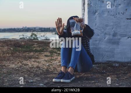 Female junkie showing STOP gesture while sitting near color wall Stock ...