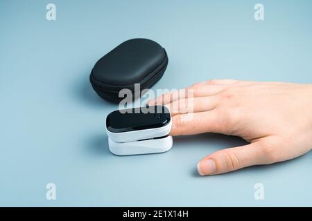 Pulse oximeter on person's finger measuring their oxygen saturation ...