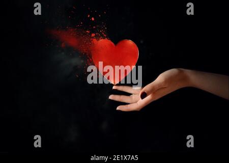 Woman hand balancing broken heart with dust and explosion Stock Photo ...